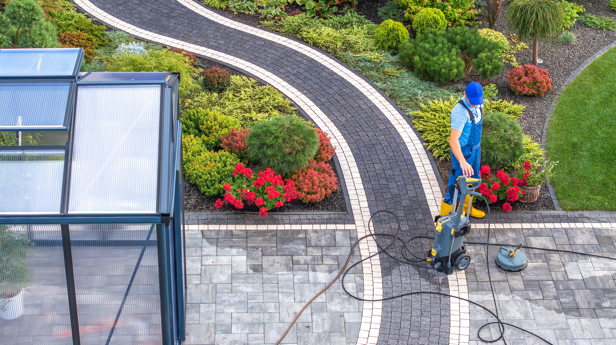 Man Cleaning His Backyard Garden Paths Using Pressure Washer - DM Landscape